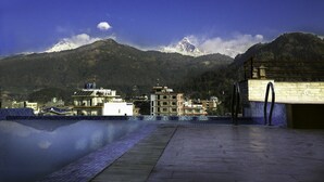 Área da piscina com vista para uma cordilheira e um hotel ao fundo.