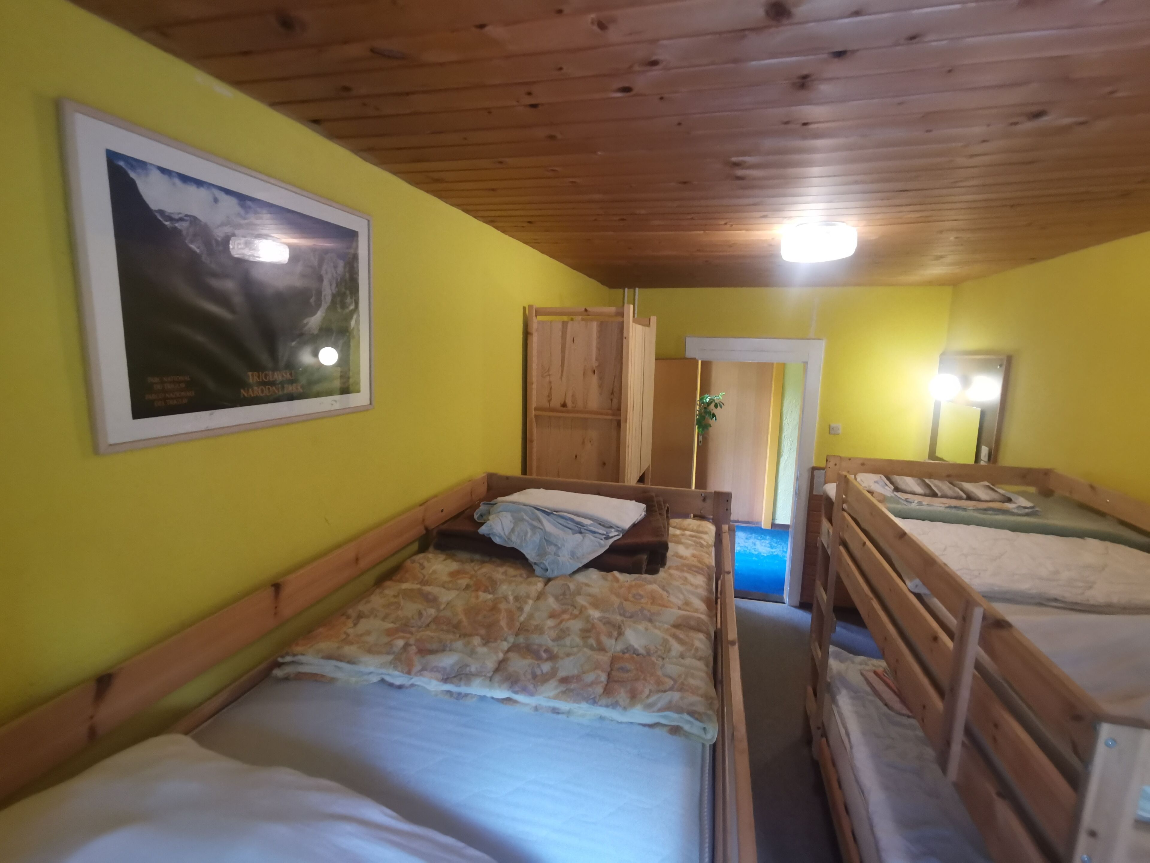 Quarto com duas beliches de madeira, um quadro na parede e teto de madeira.