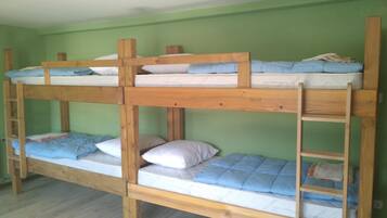 Uma cama de beliche com três andares, estrutura de madeira e uma escada do lado direito.