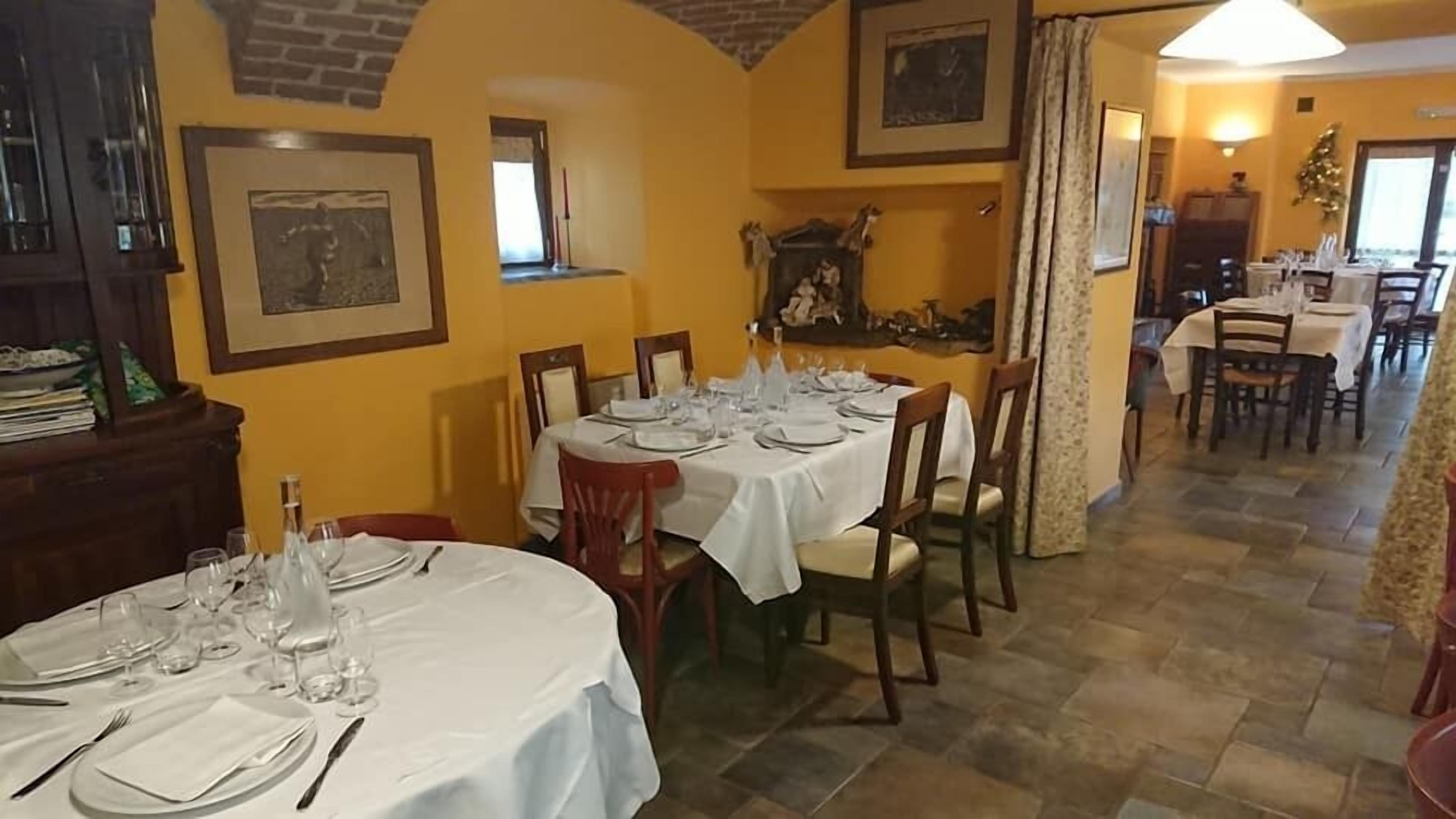 Uma área de refeições com mesas redondas preparadas para uma refeição, com toalhas de mesa brancas e cadeiras.