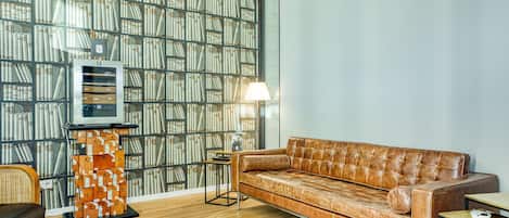 Uma sala de estar moderna com um sofá de couro, uma estante de madeira, um tapete de couro bovino e um abajur.
