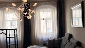 Uma sala de estar moderna com um sofá cinza, uma mesa de centro de madeira e um candelabro exclusivo.