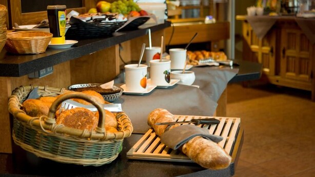 Um buffet de café da manhã com pães, doces e frutas.