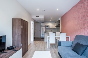 Um apartamento moderno com área de jantar, cozinha compacta e sala de estar com sofá.
