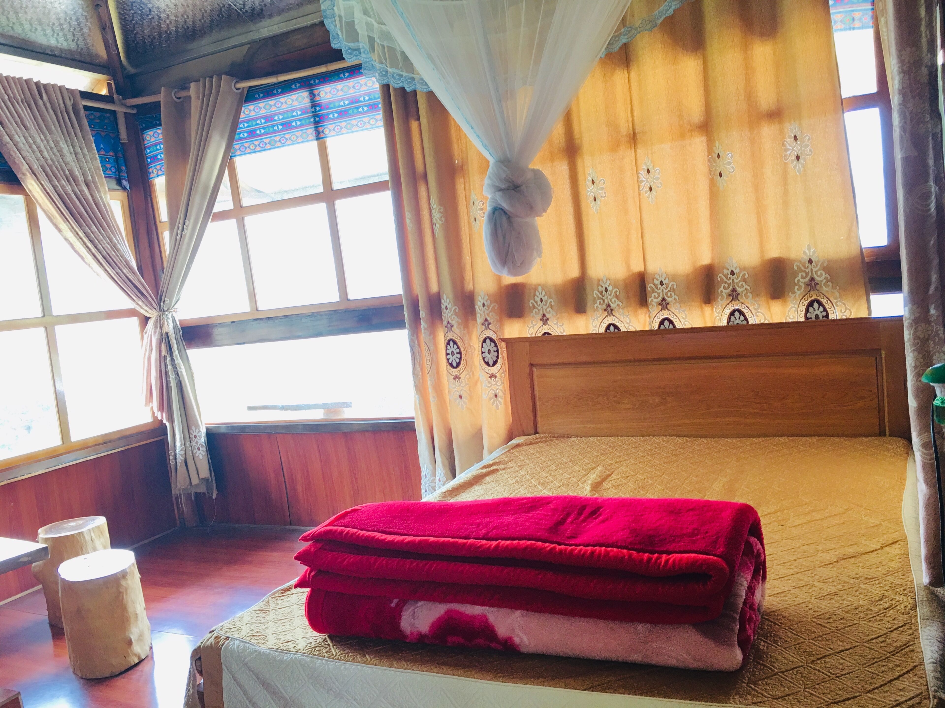 Quarto com cama, cabeceira de madeira e janela com cortinas.