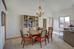 Uma sala de jantar com mesa e cadeiras de madeira, um candelabro e uma estante com objetos decorativos.