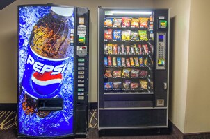 Duas máquinas automáticas, uma com o logotipo da Pepsi e outra com diversos lanches.
