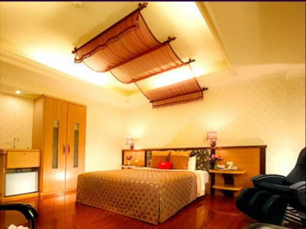 Quarto de hotel com uma cama grande, uma escrivaninha, uma cadeira e um guarda-roupa.