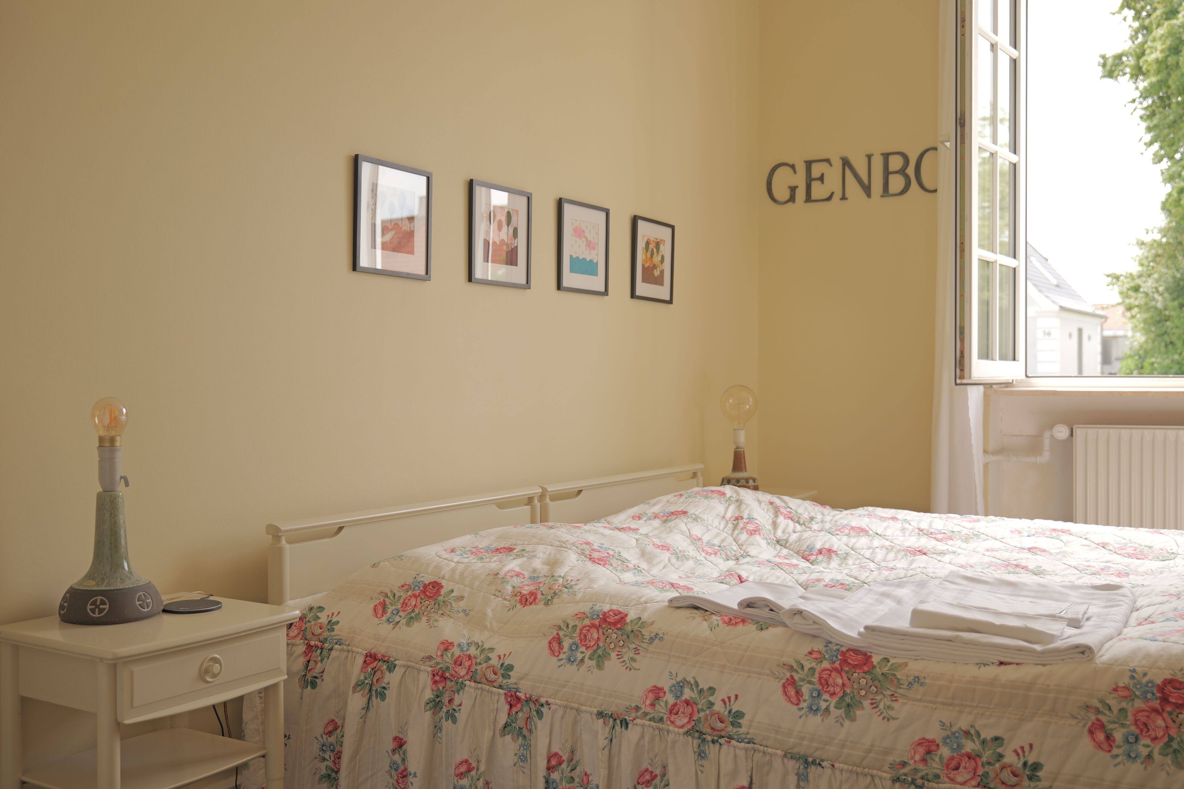 Um quarto com uma cama, mesa de cabeceira, luminária e janela.
