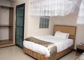 Quarto com cama, guarda-roupa, mesa de cabeceira com telefone e janela com vista.
