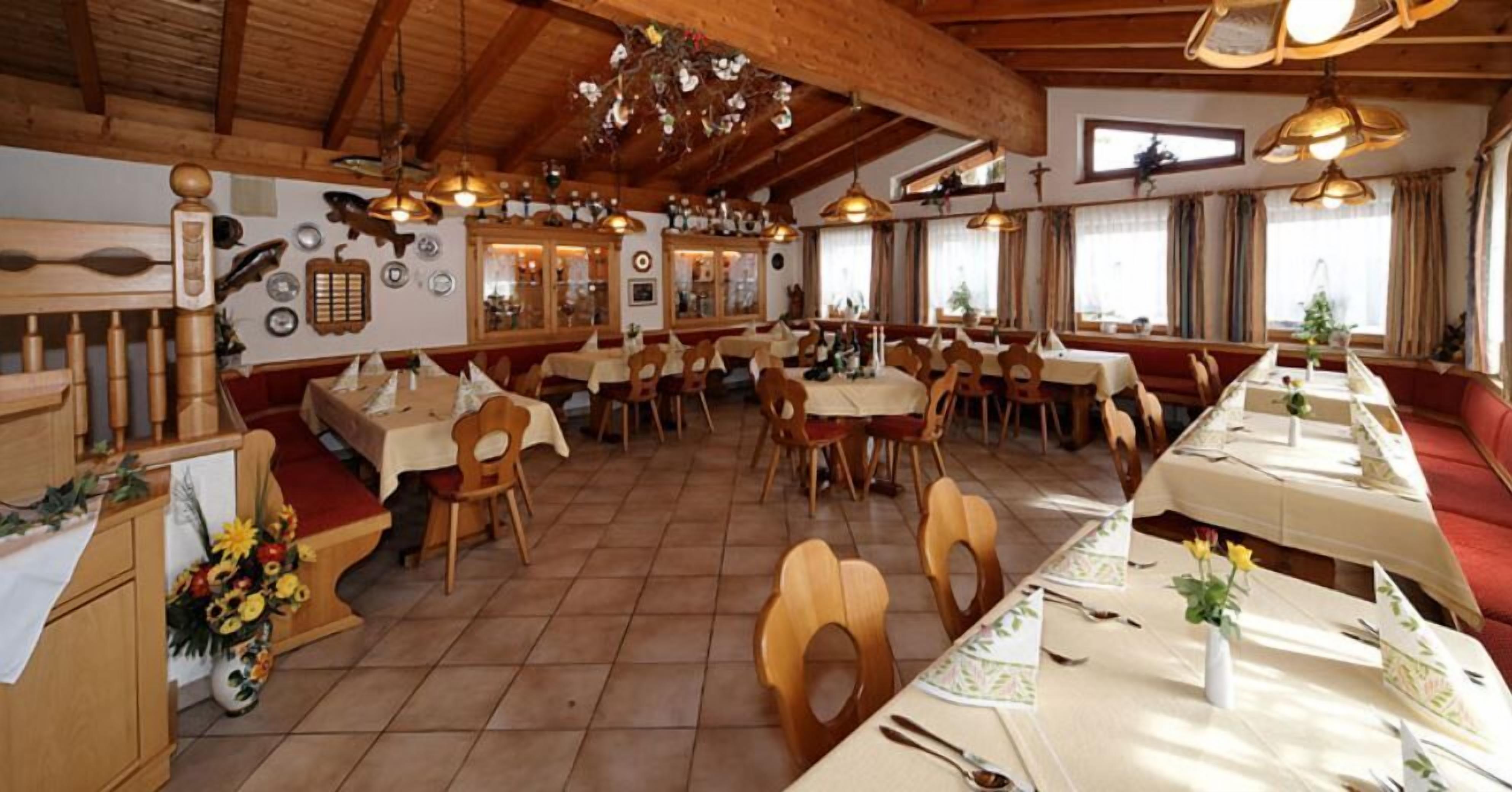 Restaurante com móveis de madeira, várias mesas de jantar e decoração rústica.