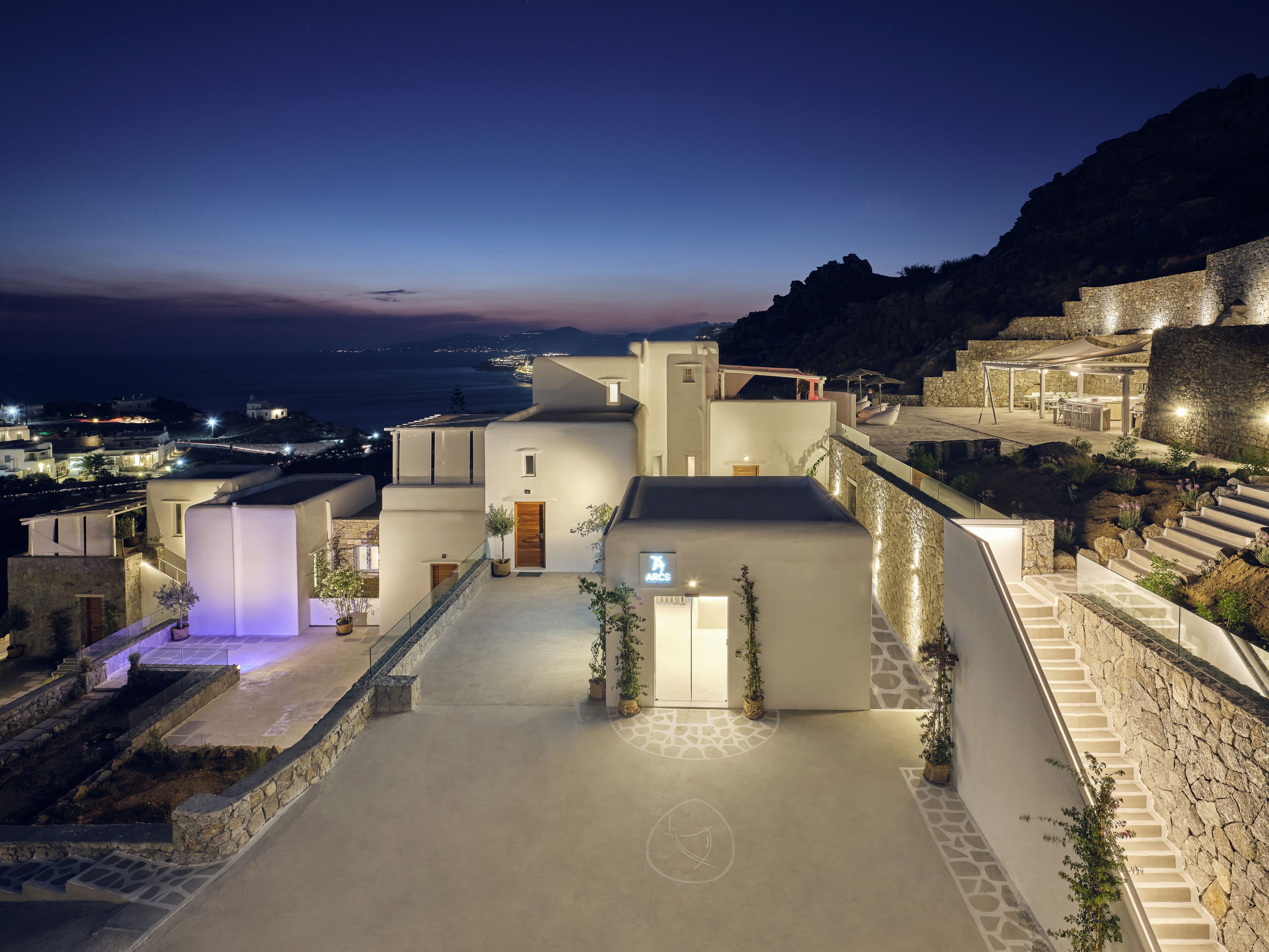 Uma vila costeira com edifícios de pedra, uma área central pavimentada e vista para o mar.
