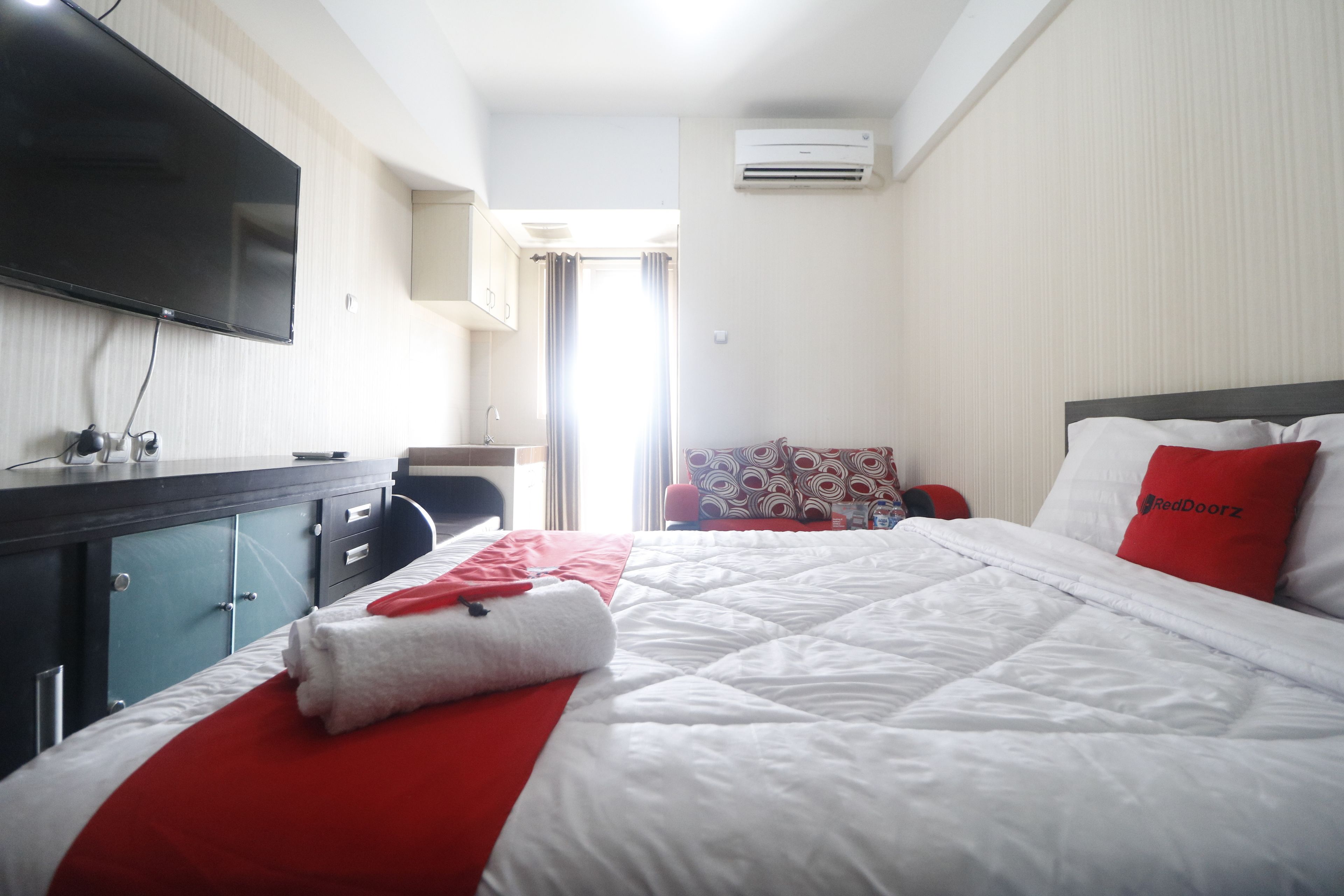 Quarto de hotel com cama, escrivaninha, televisão de tela plana e ar condicionado.