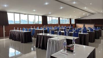 Uma sala de conferências com várias mesas, cadeiras e garrafas de água.