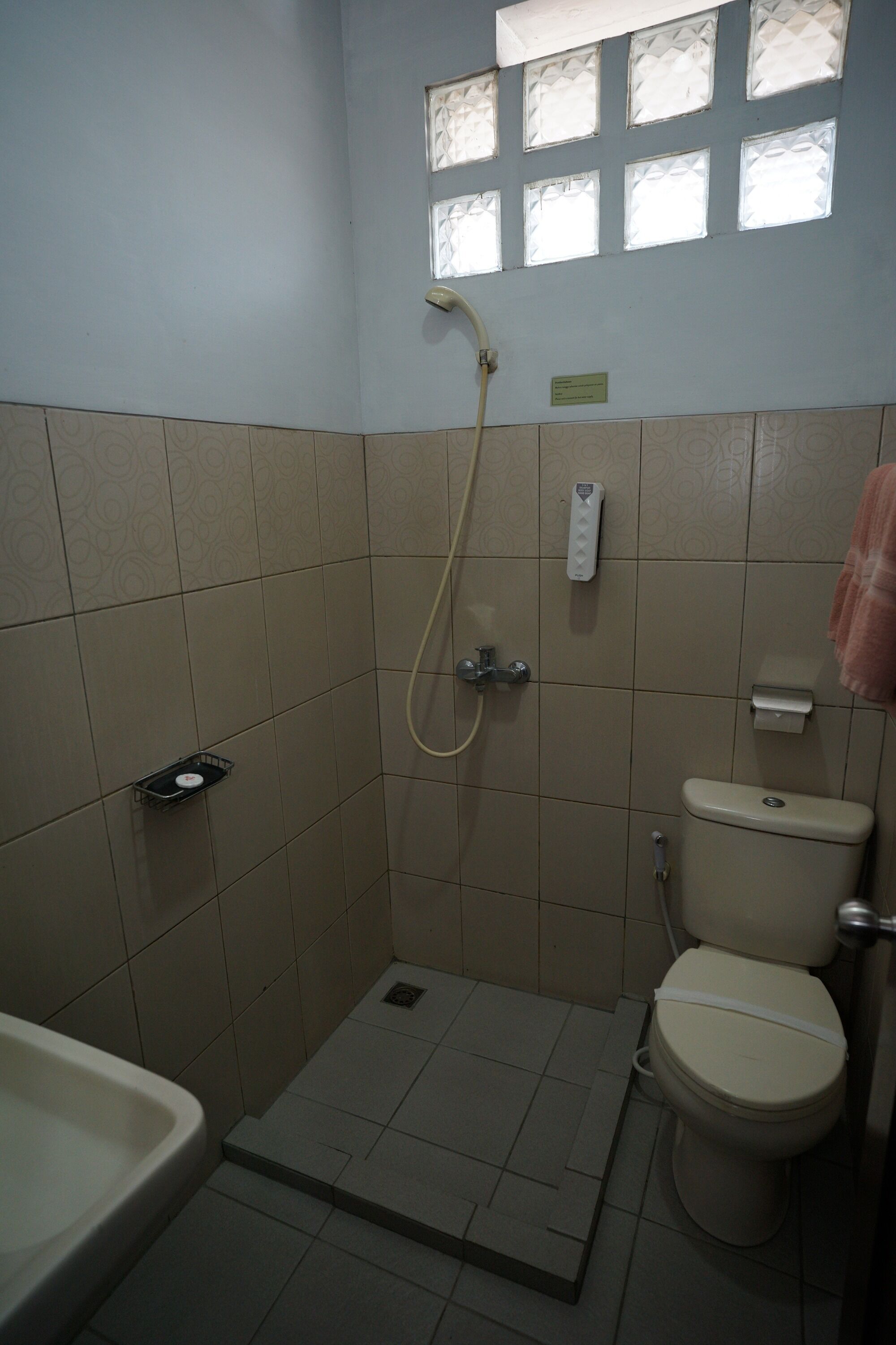 Casa de banho com chuveiro, sanita e lavatório.