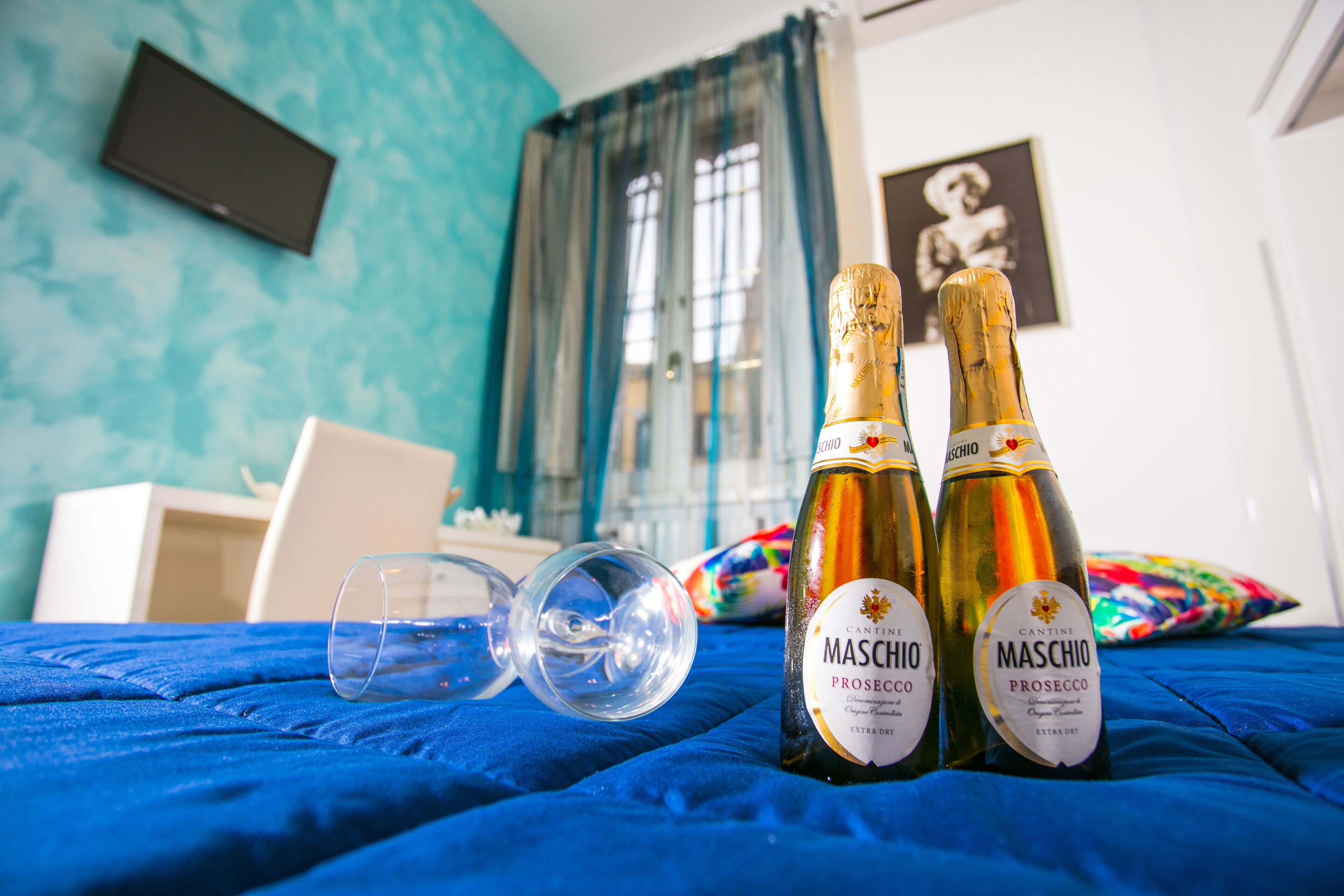 Duas garrafas de Prosecco Cantina Maschio sobre um lençol azul, com uma taça de vinho transparente ao lado.