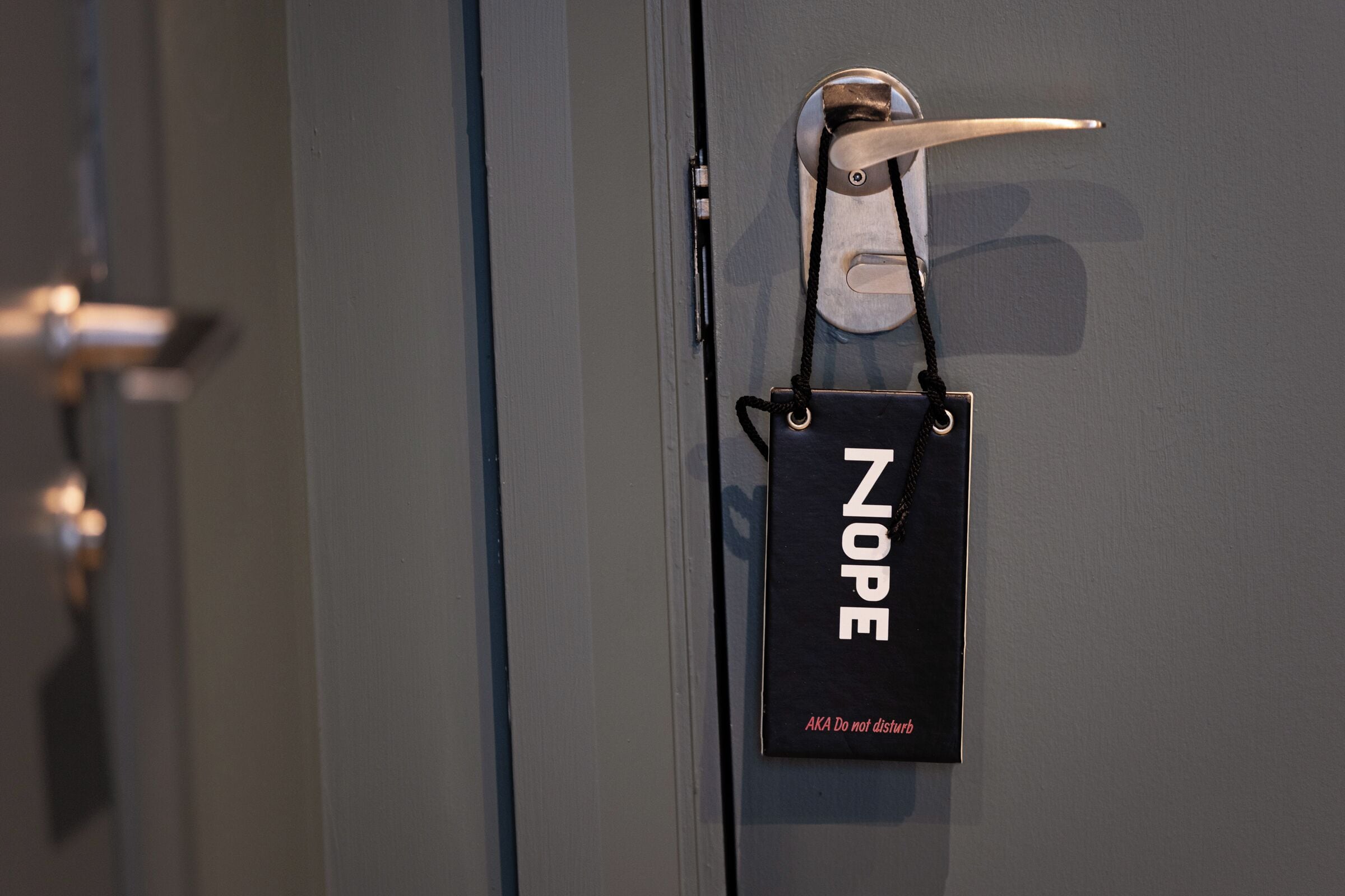 Uma porta com puxador e uma placa preta com texto branco.