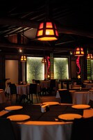 Restaurante com mesas postas para refeição, iluminado por lustres com design de árvore.