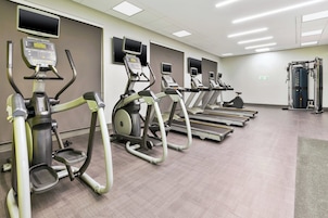 Academia com esteiras, elípticos e máquina de musculação.