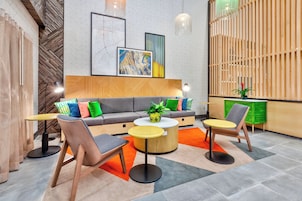 Uma área de estar moderna com sofá, cadeiras, mesa de centro e uma planta decorativa.