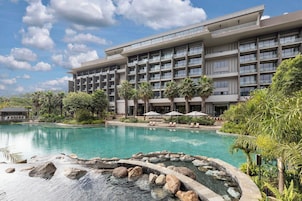 Um hotel com uma piscina grande, várias varandas e paisagismo exuberante.