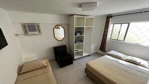 Quarto com cama, guarda-roupa, uma mesinha e janela.