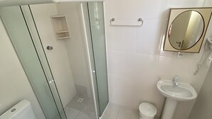 Uma casa de banho com sanita, lavatório e cabine de duche em vidro.