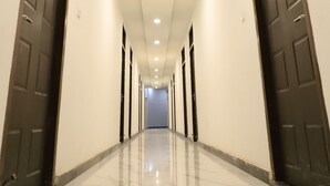 Um corredor longo e bem iluminado, com portas em ambos os lados, que conduz a um quarto distante.