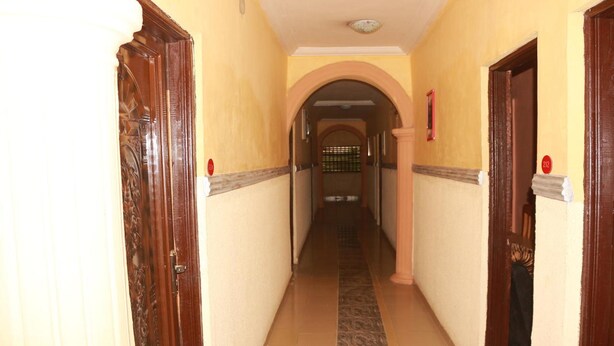 Um corredor com piso de mármore, portas de madeira e parede revestida de azulejos.