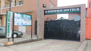 Entrada de hotel com um grande letreiro para Hummer Hotels, uma entrada com portão e um carro estacionado.