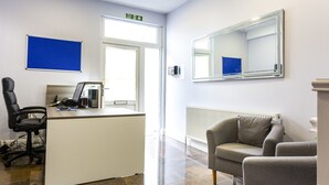 Um espaço de escritório moderno com uma mesa de recepção, um computador, uma cadeira e um sofá.