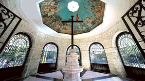 Um edifício histórico com uma coluna central, janelas em arco e um mural no teto.