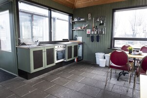 Cozinha compacta com fogão, pia e armários, área de jantar com cadeiras vermelhas e uma janela grande que proporciona iluminação natural.