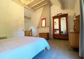 Quarto com uma cama grande, cômoda de madeira, espelho e lareira.