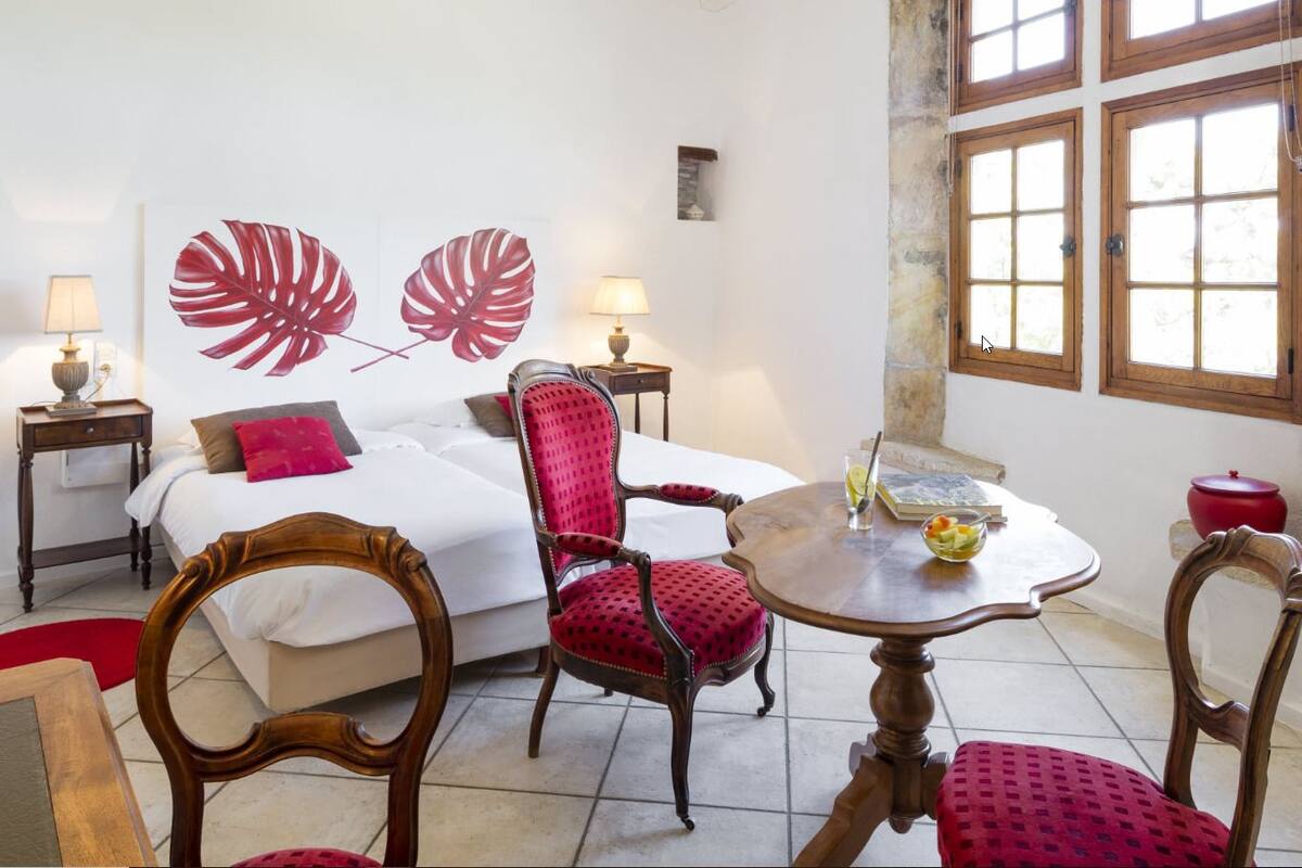 Quarto de hotel com uma cama, duas mesas de cabeceira, uma mesa e cadeiras.