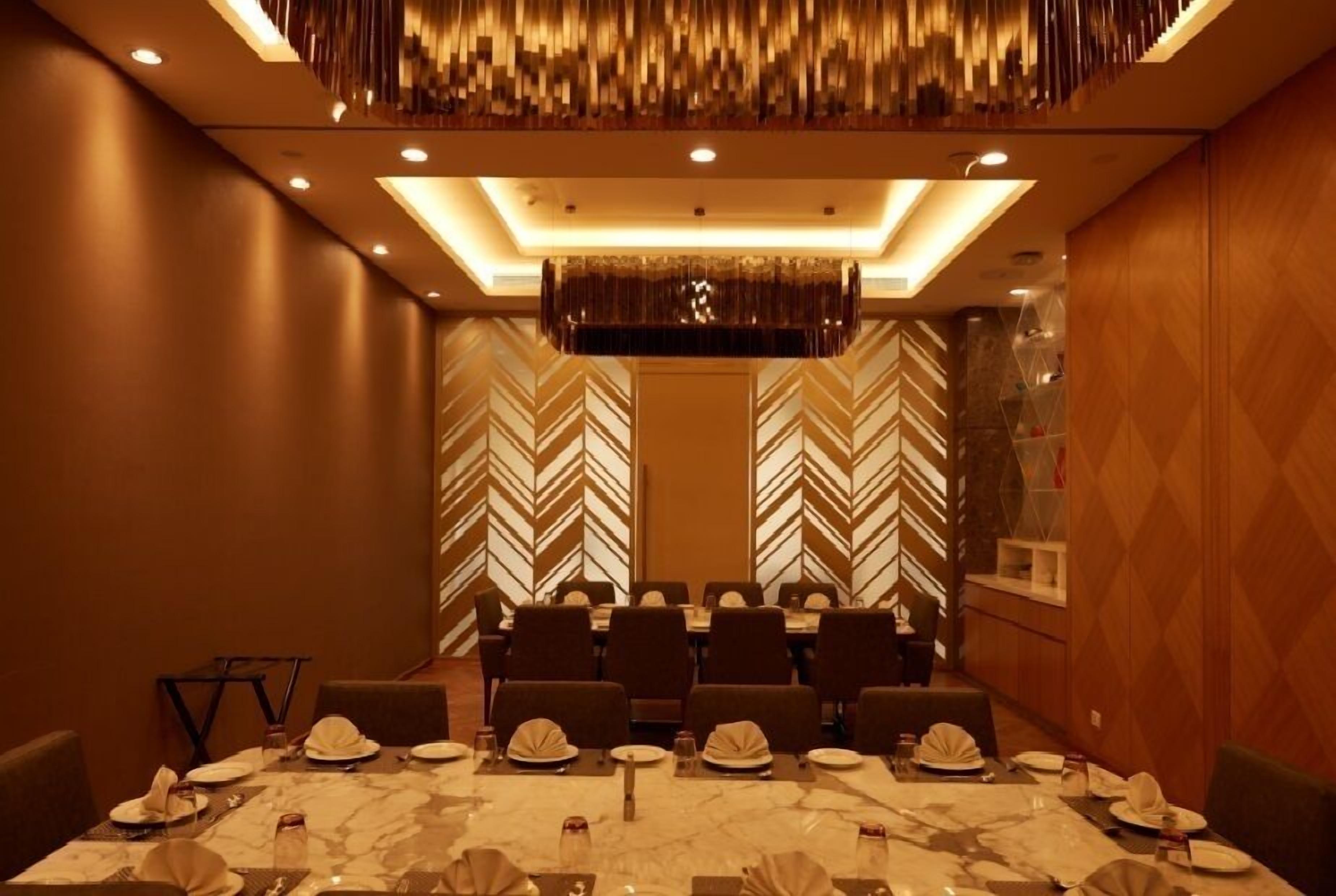 Uma sala de conferências com uma mesa comprida preparada para uma reunião, equipada com cadeiras e um candelabro.