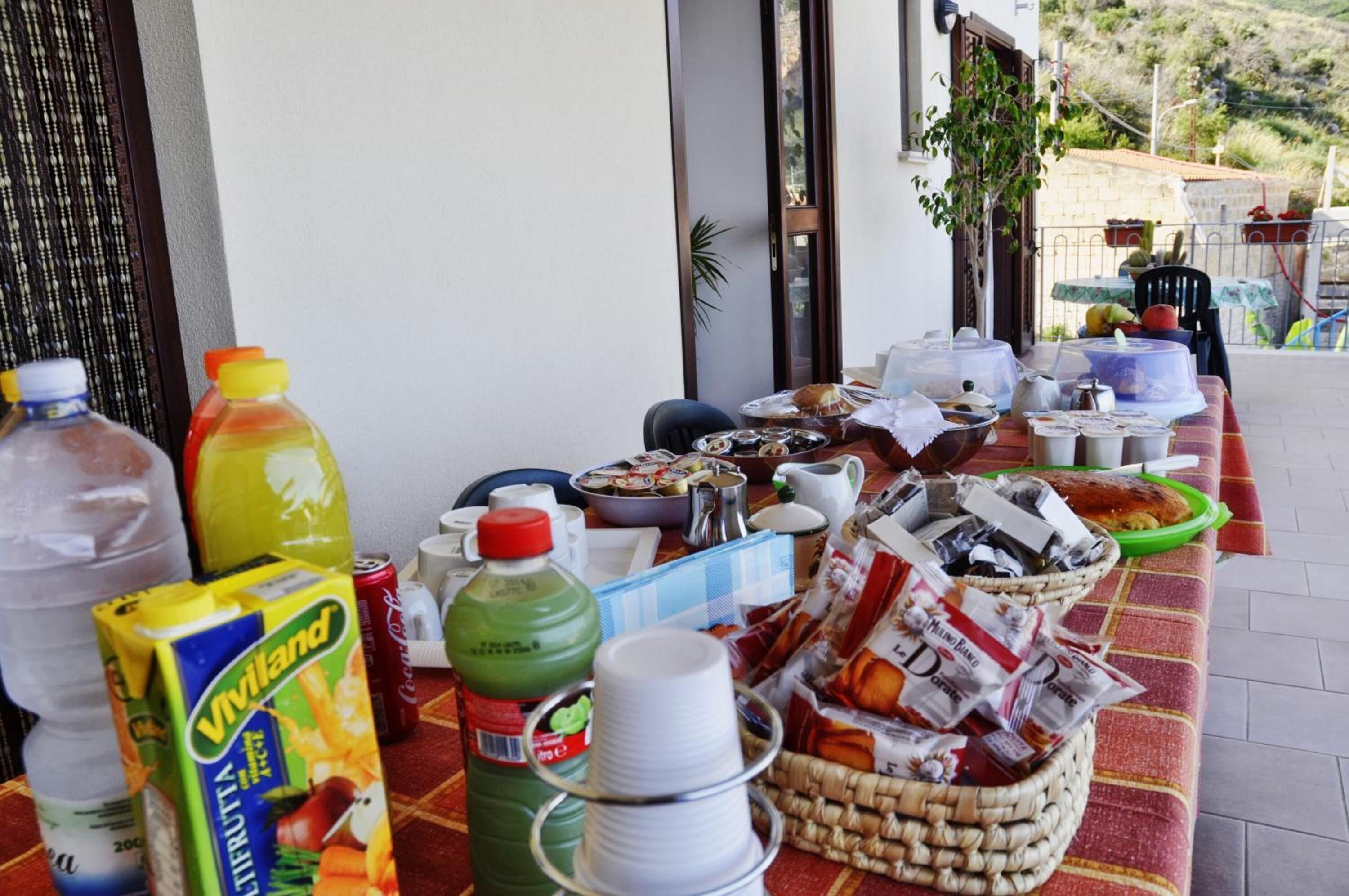 Disposição de buffet de café da manhã com diversos alimentos, bebidas e acompanhamentos sobre uma mesa.