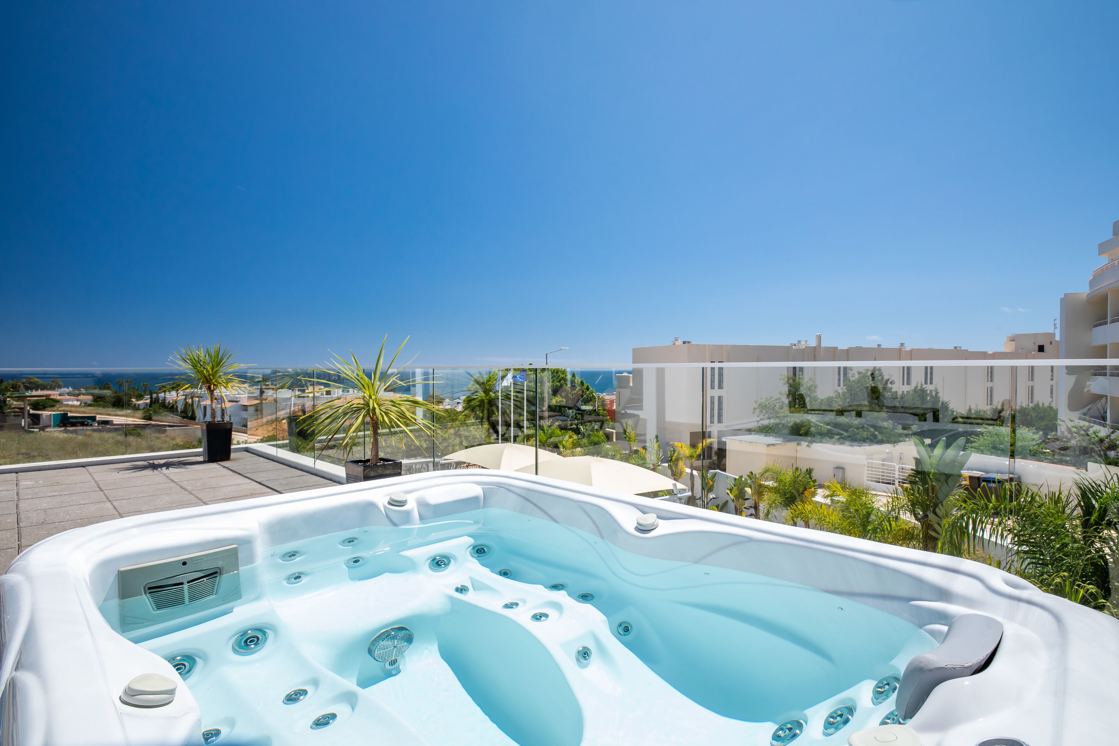 Uma banheira de hidromassagem com vista clara para o mar e edifícios ao redor.