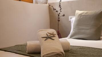 Uma cama bem arrumada com uma toalha verde e uma toalha enrolada decorada com uma estrela-do-mar.