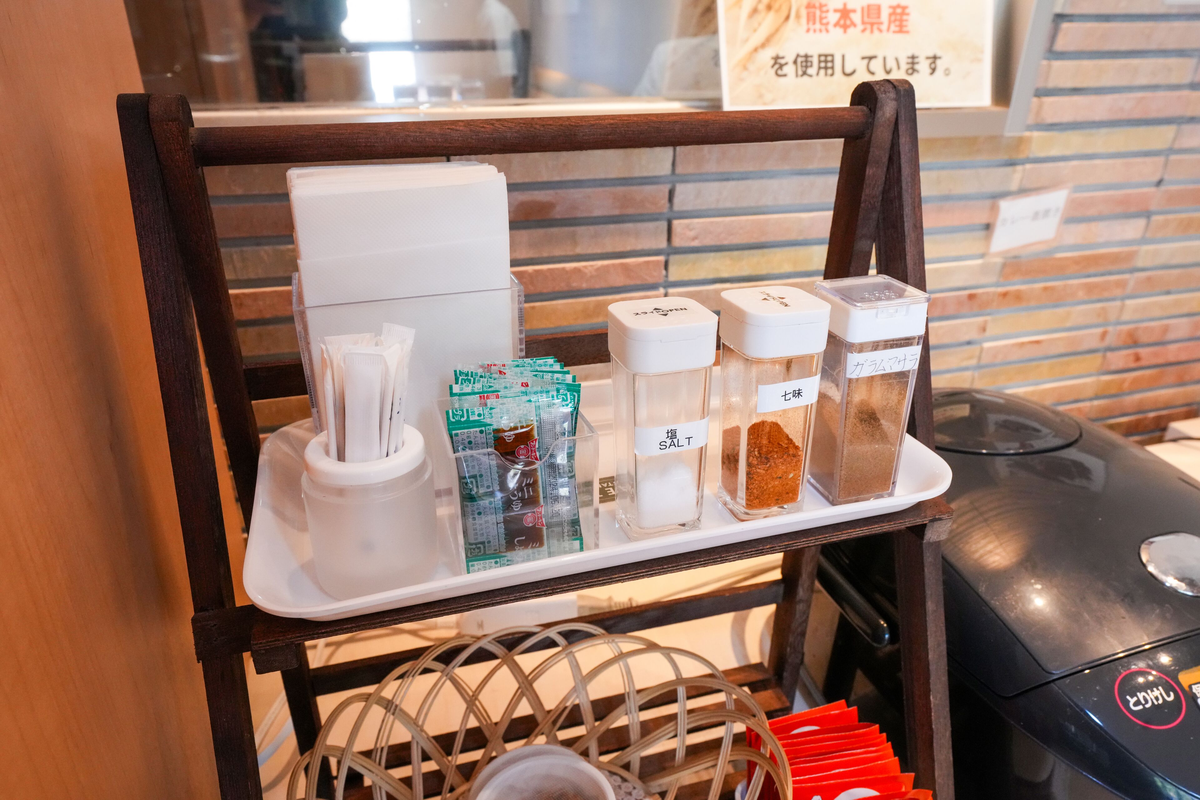 Um espaço com estação de café, máquina de café, sal, açúcar e pacotes de leite.