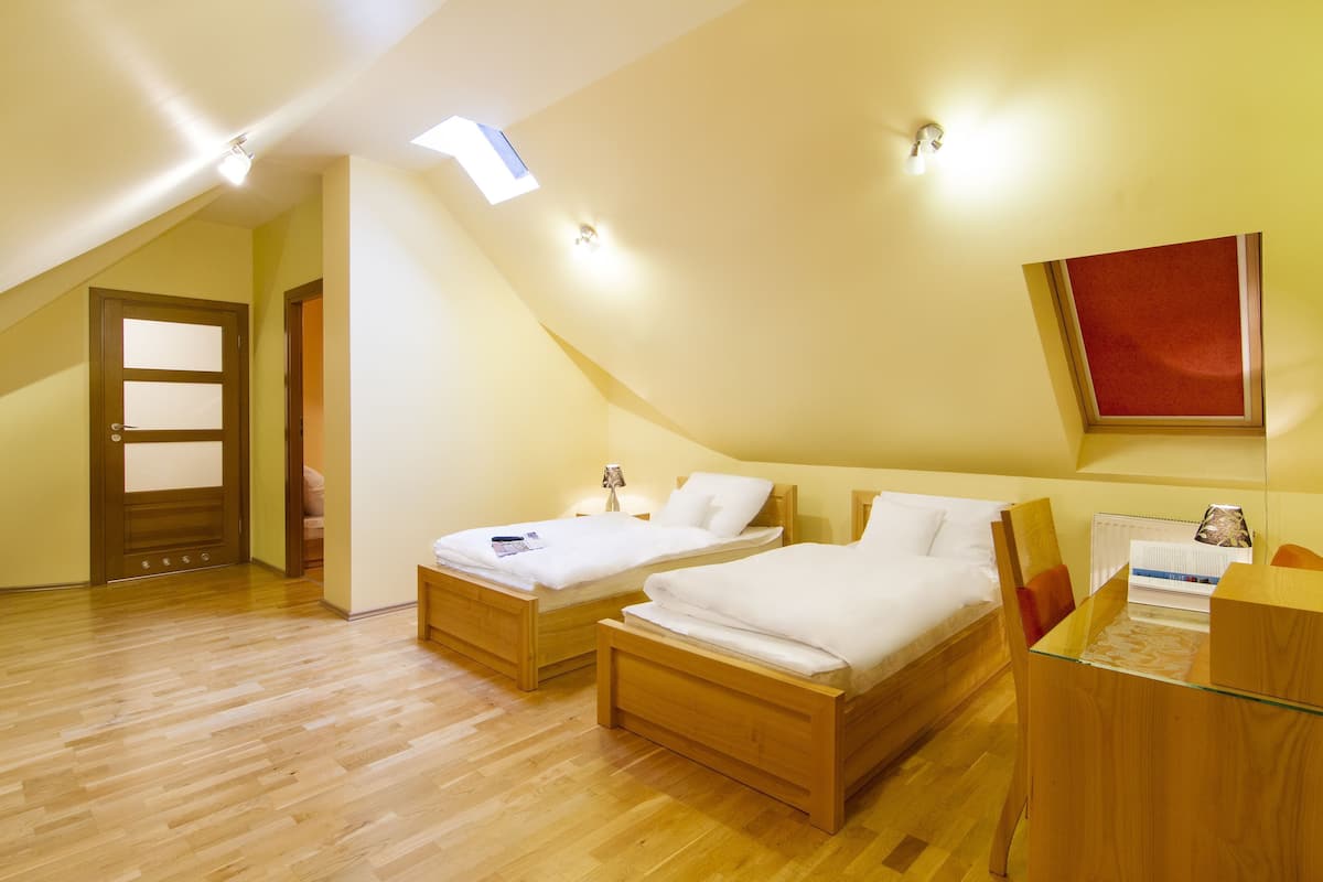 Quarto com duas camas de madeira, uma escrivaninha, uma cadeira e uma parede com detalhes em vermelho.