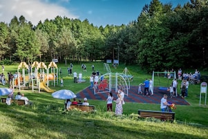 Um parque com equipamentos de recreação, bancos e uma área gramada.