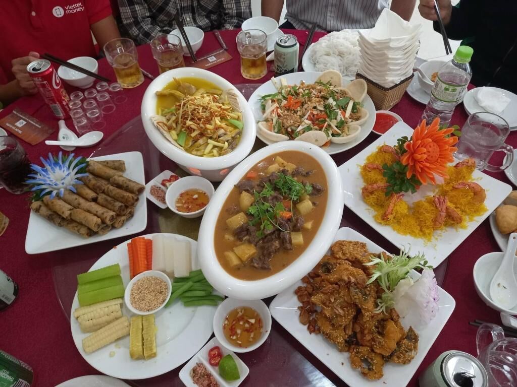 Uma mesa com diversos pratos, incluindo uma tigela de sopa, um prato com frituras e um refogado de legumes.