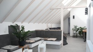 Um loft moderno com teto inclinado, assentos embutidos, espaço para refeições e um vaso de planta.