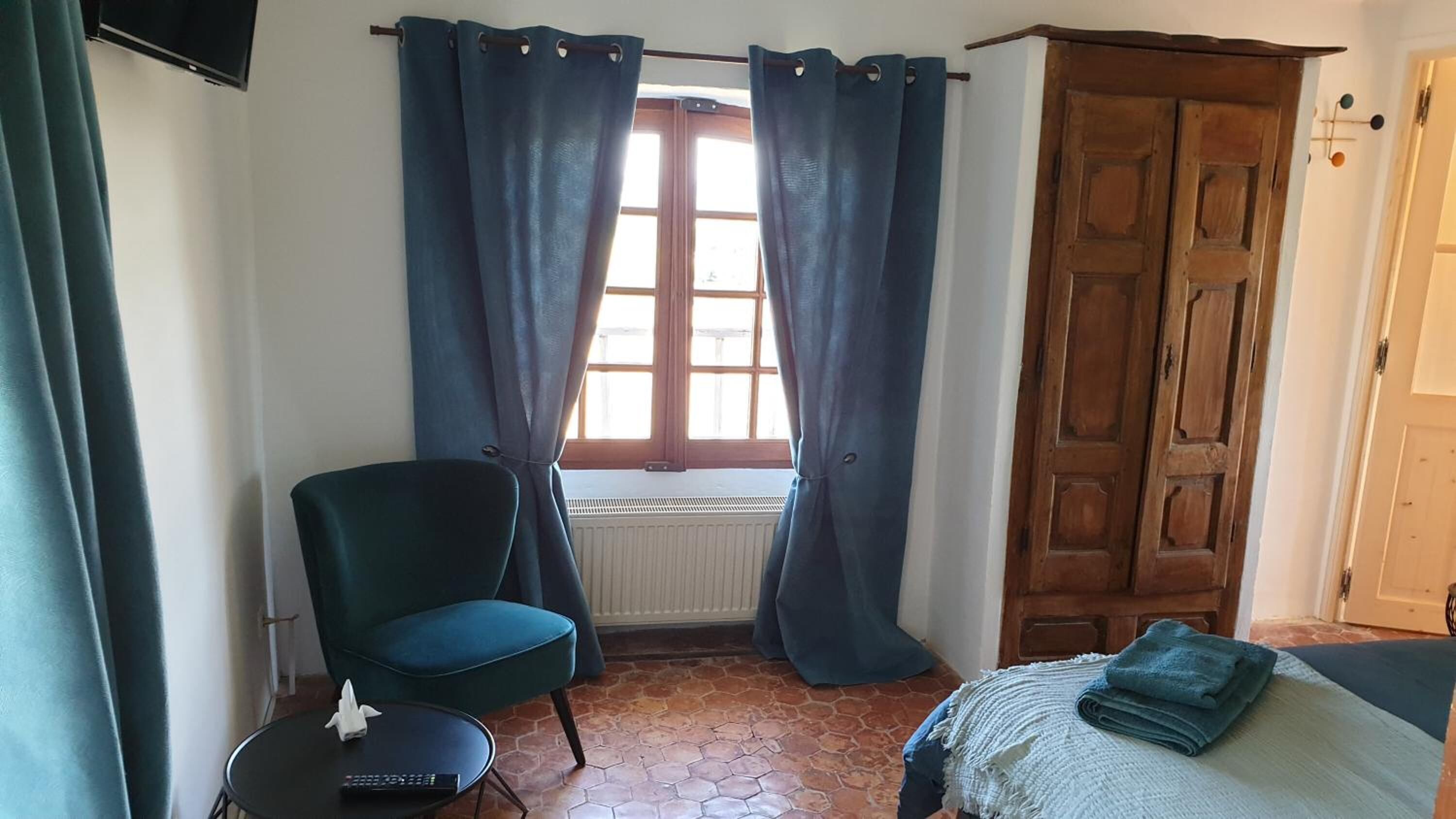 Quarto com janela, cadeira, cama e radiador.