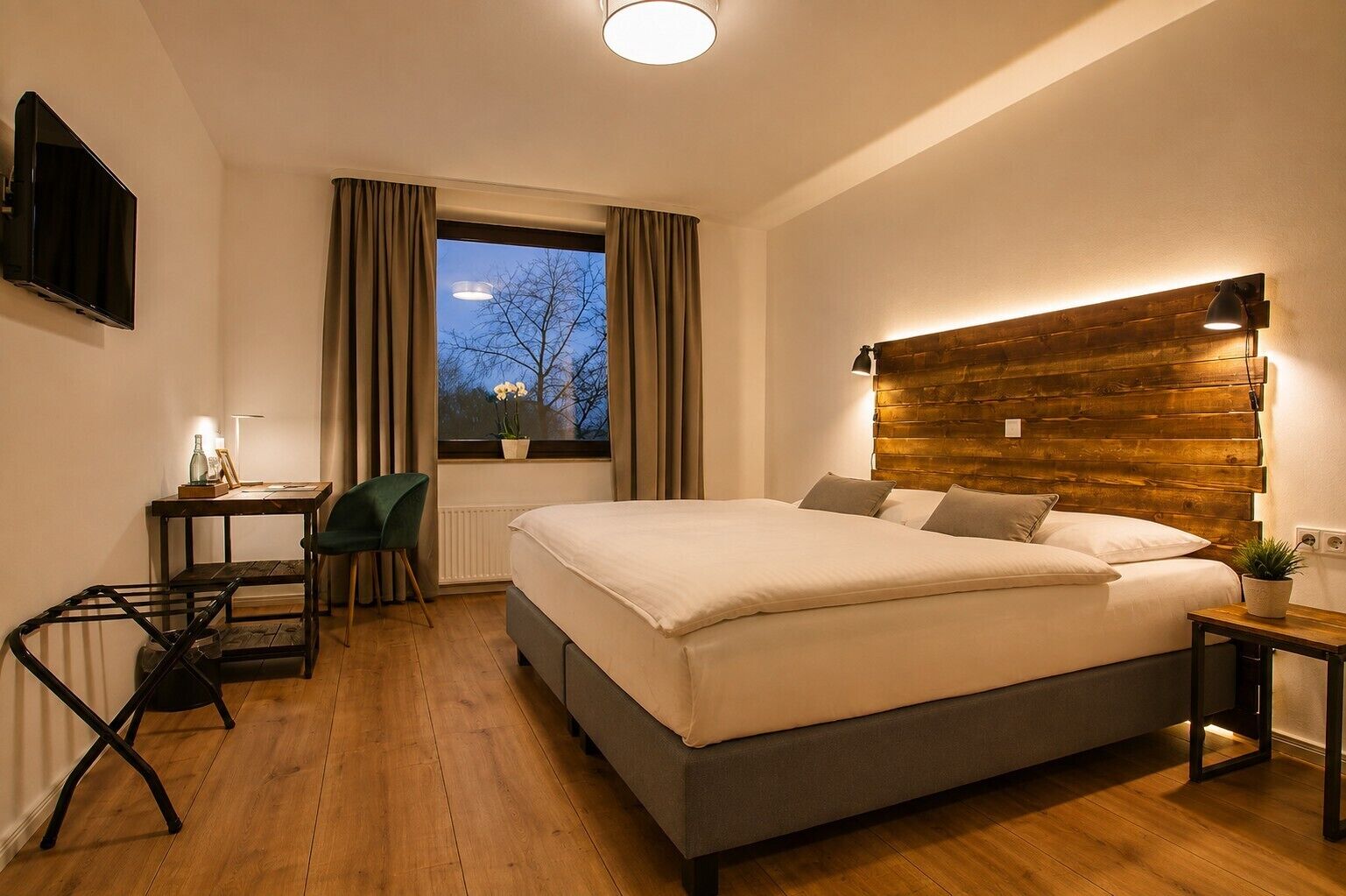 Um quarto moderno com uma cama grande, uma escrivaninha, uma cadeira e uma janela com cortinas.