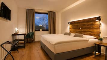 Um quarto moderno com uma cama grande, uma escrivaninha, uma cadeira e uma janela com cortinas.