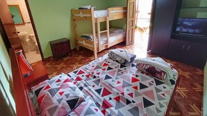 Um quarto com cama beliche, escrivaninha, espelho e televisão.