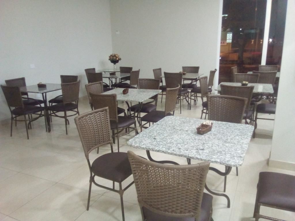 Uma sala de jantar com várias mesas e cadeiras, dispostas em um espaço amplo.