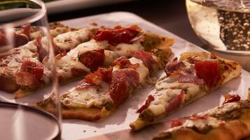 Uma mesa com fatias de pizza, um copo de vinho branco e uma salada.